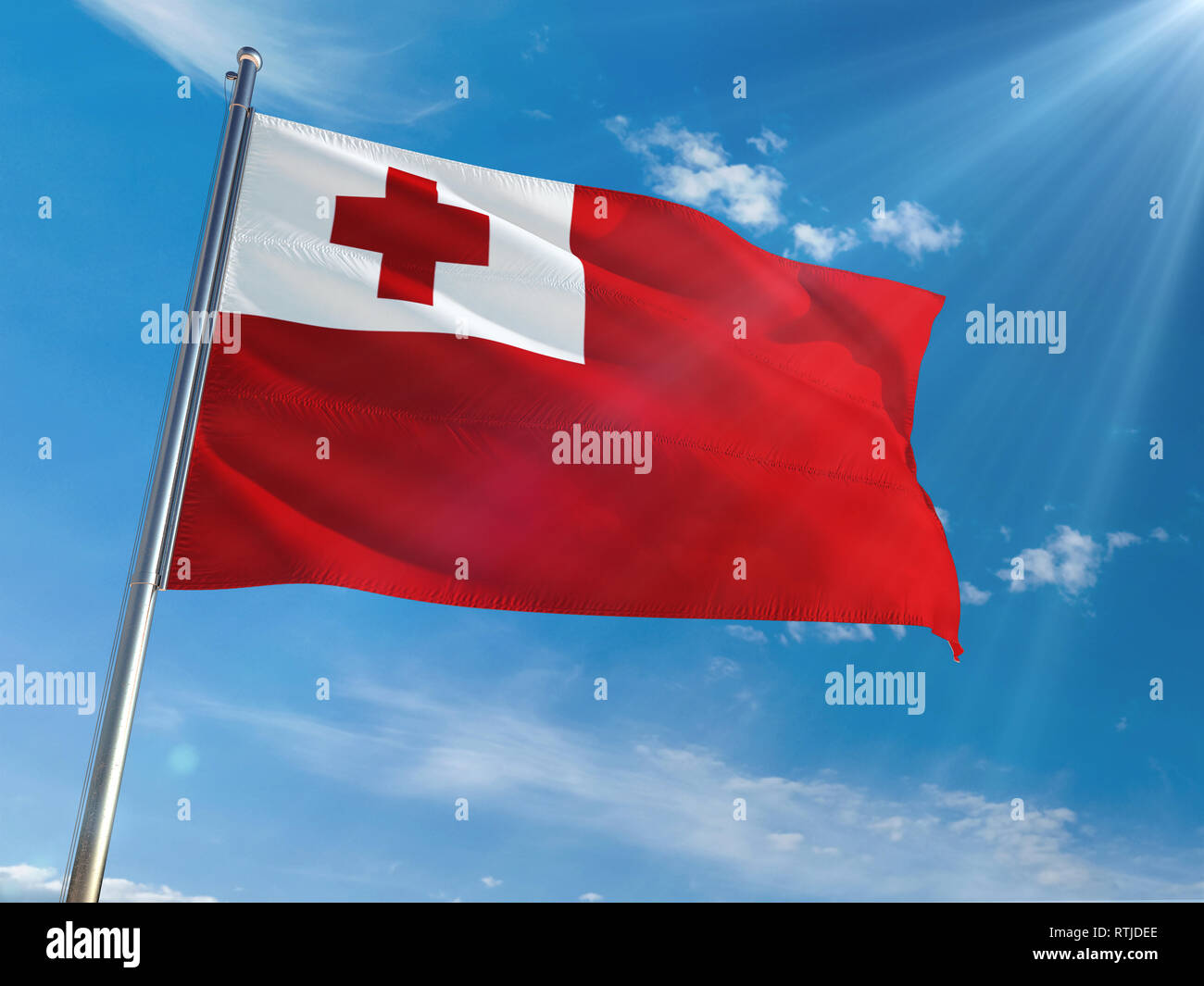 Tonga National Flag Waving on pole against sunny blue sky background ...