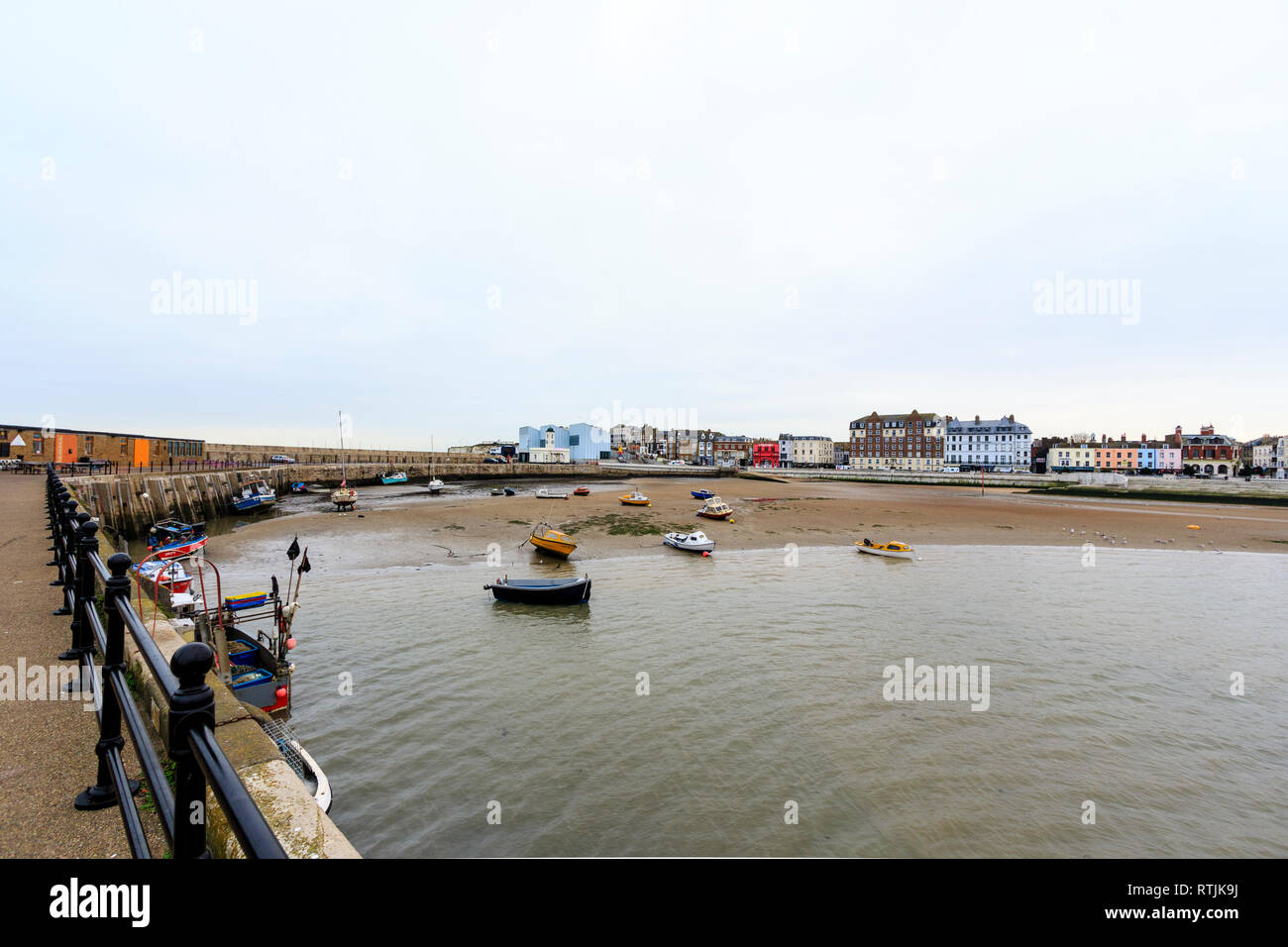 Margate harbour, curved stone jetty wall, small boats in harbour and ...