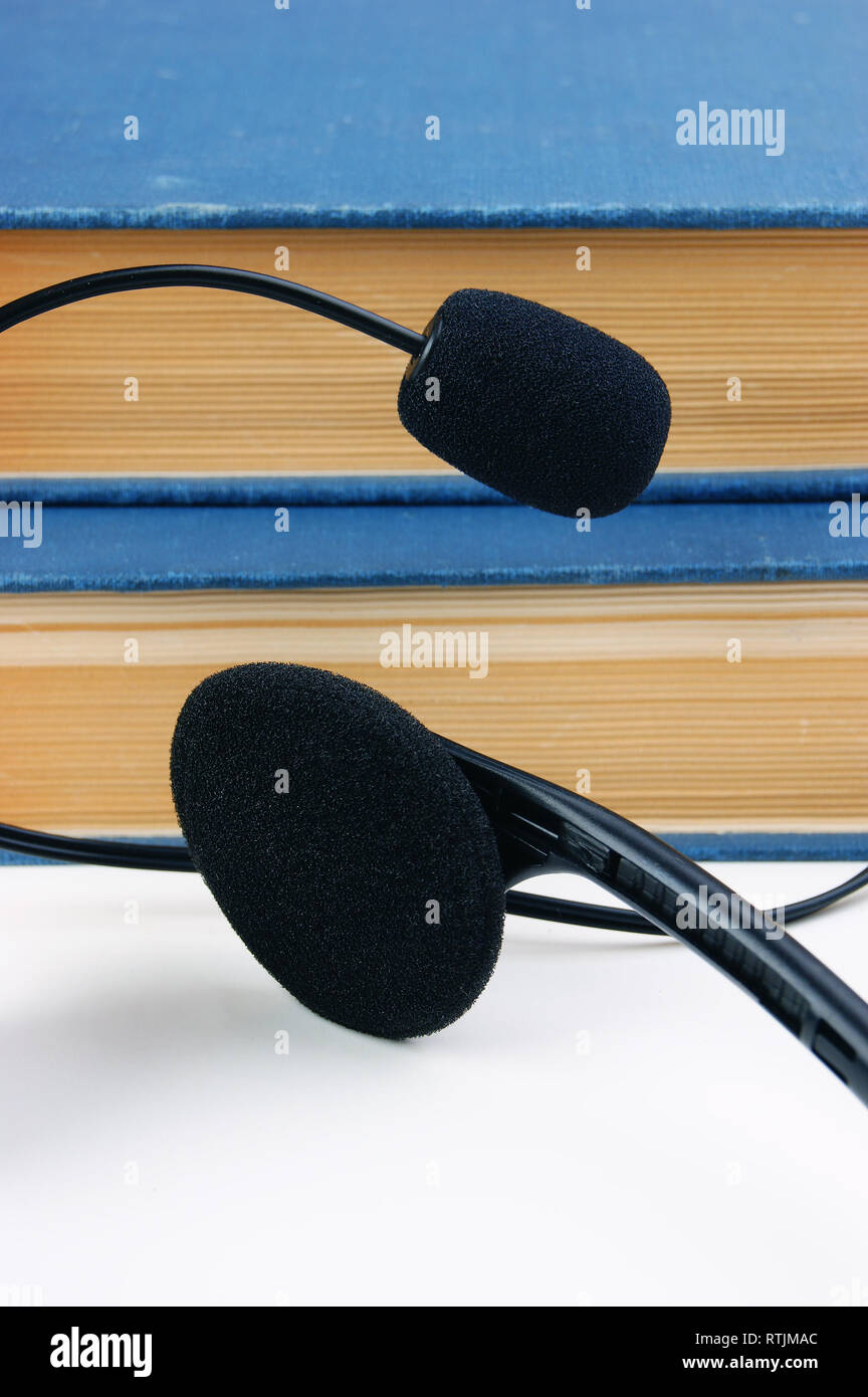 Headphones with a microphone and a stack of books on white background ...