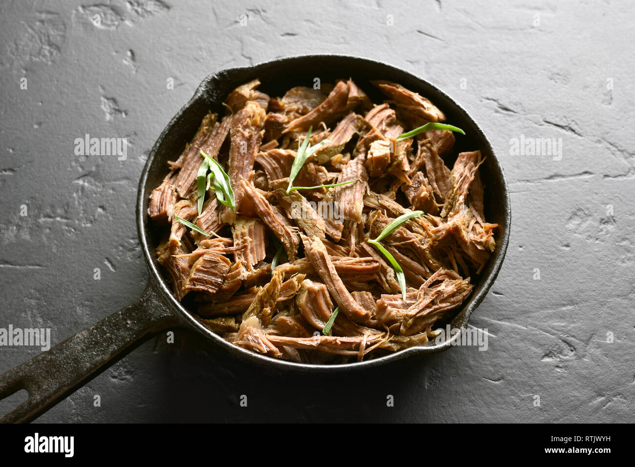 Slow cooker italian beef for sandwiches in frying pan on black stone ...