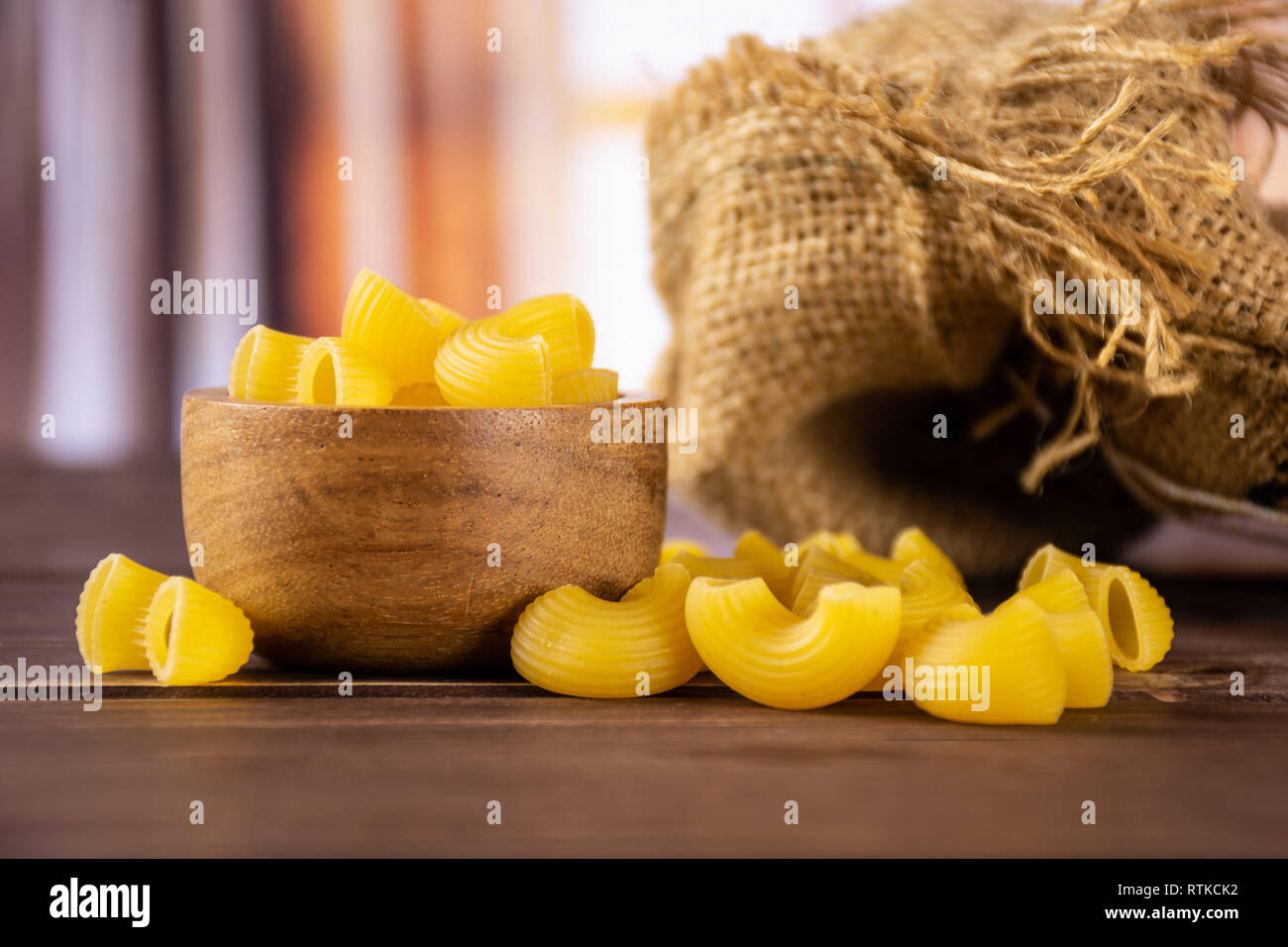 Lot of whole yellow raw pasta pipe rigate variety with wooden bowl with ...