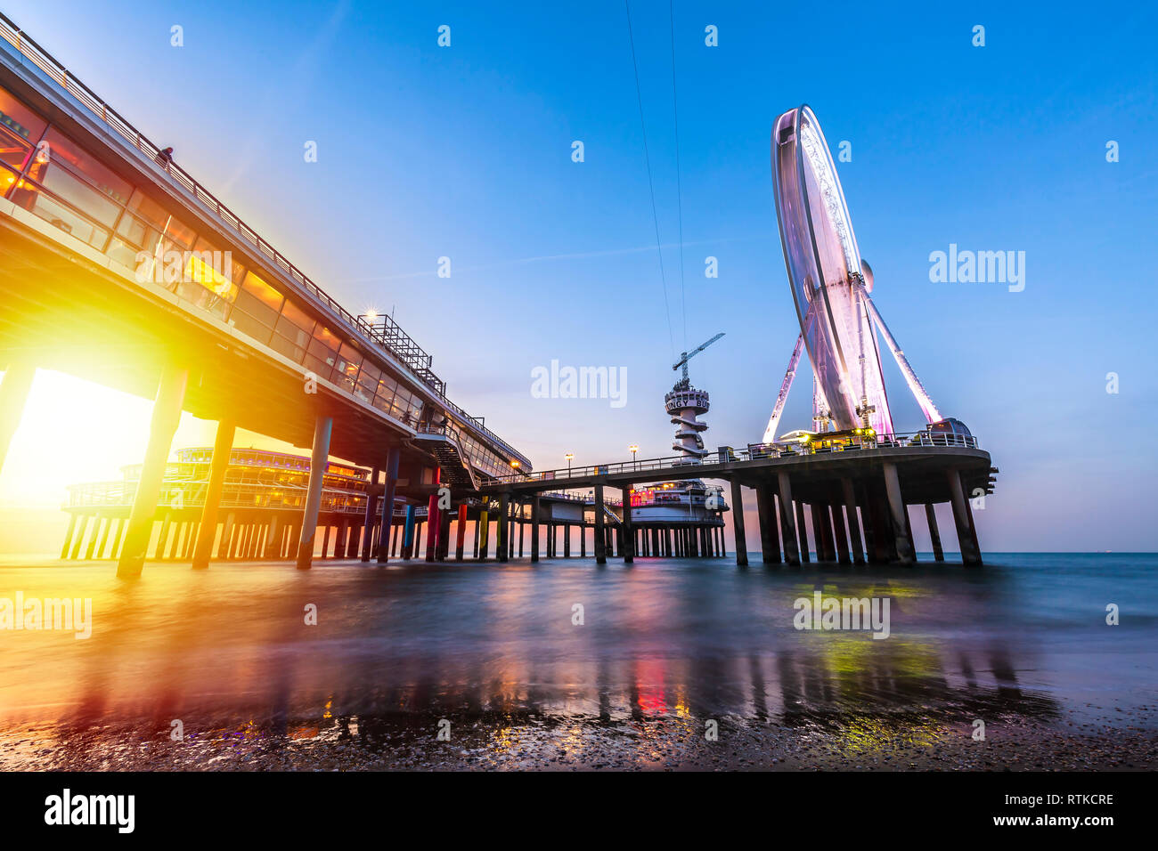 Colorful sunset on coastline, beach, pier and ferris wheel ...