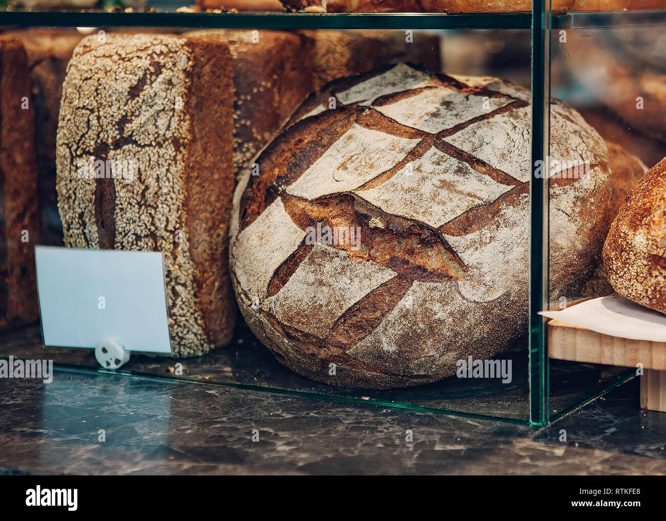 Variety of breads displayed through a clear glass display case Stock ...