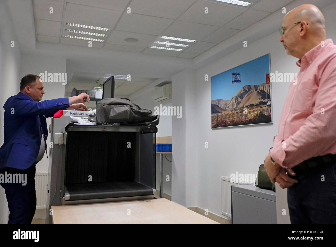 Security guard inspecting handbags of visitors through X-ray scanner ...