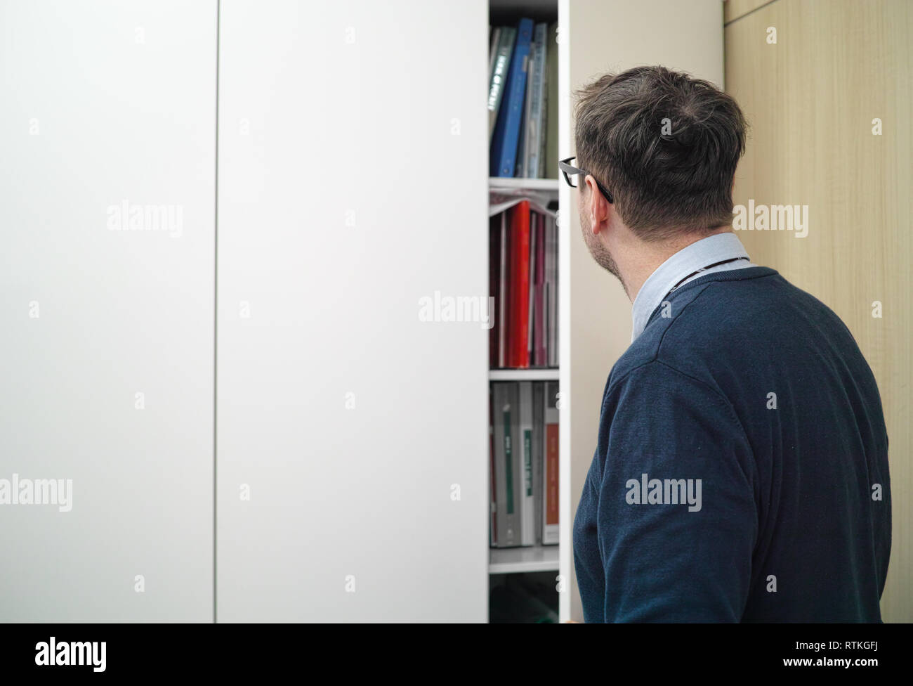 A man looking into a filing cabinet as he opens it Stock Photo - Alamy