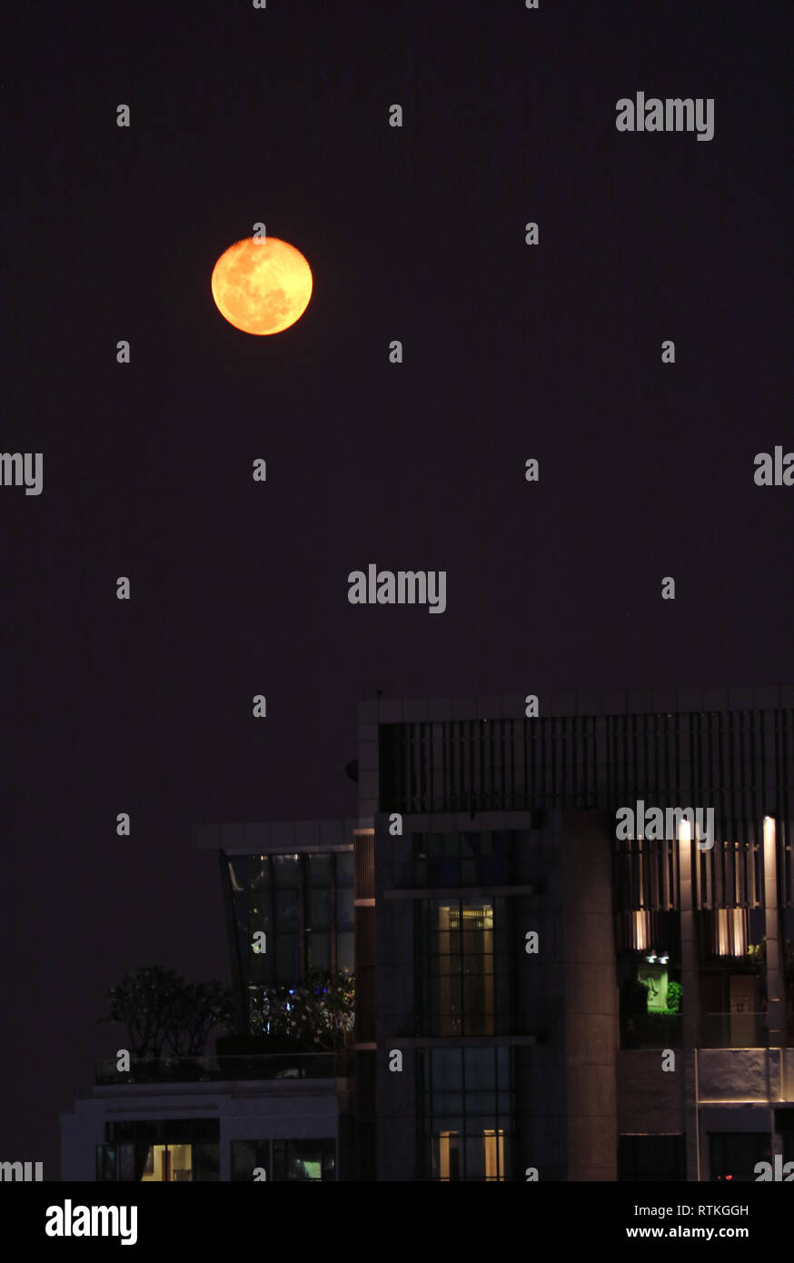 Brightly orange color full moon over the city of Bangkok, Thailand ...