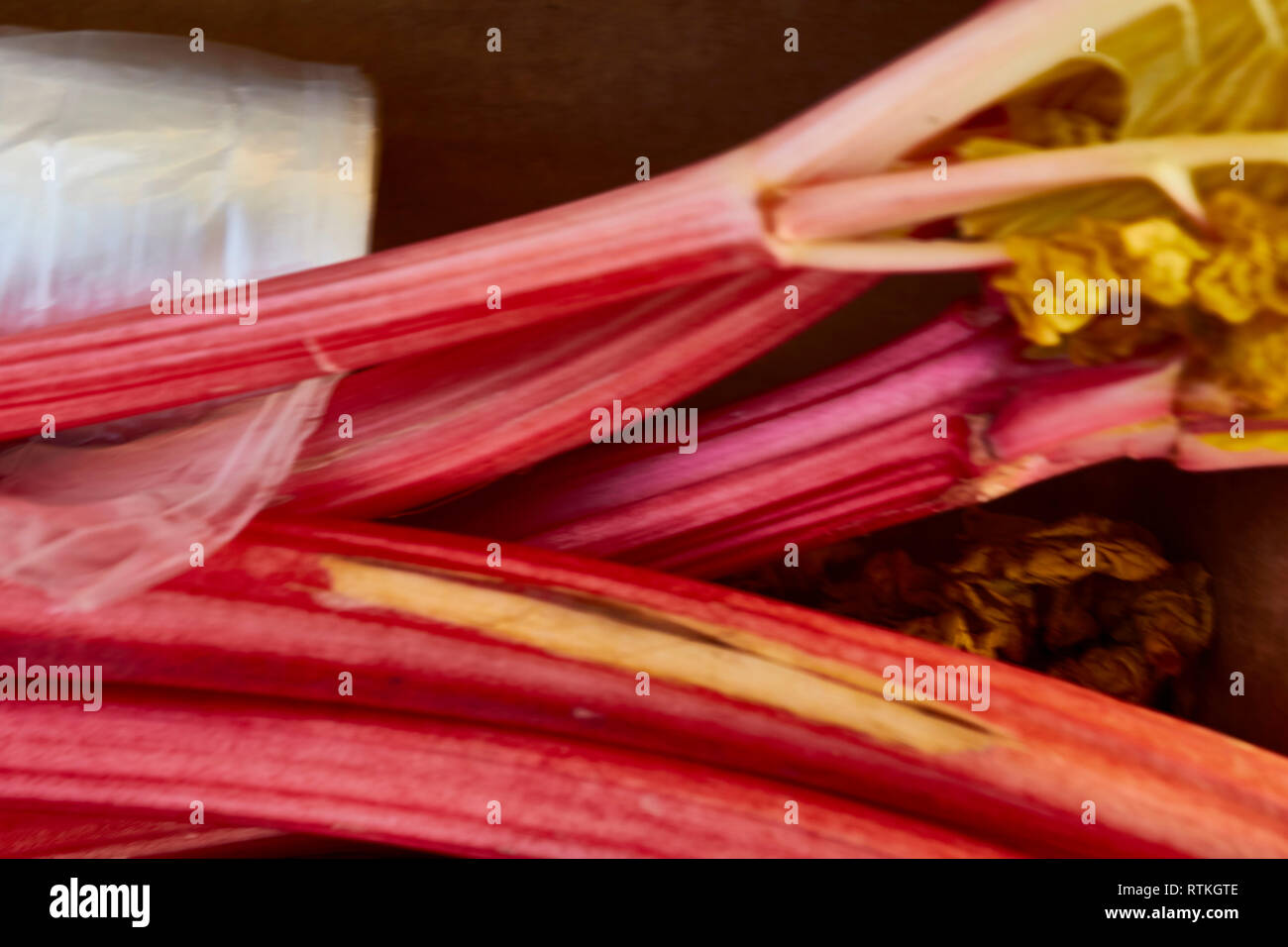 Bunch of crimson red rhubarb stalks and green leaves on sale in England ...