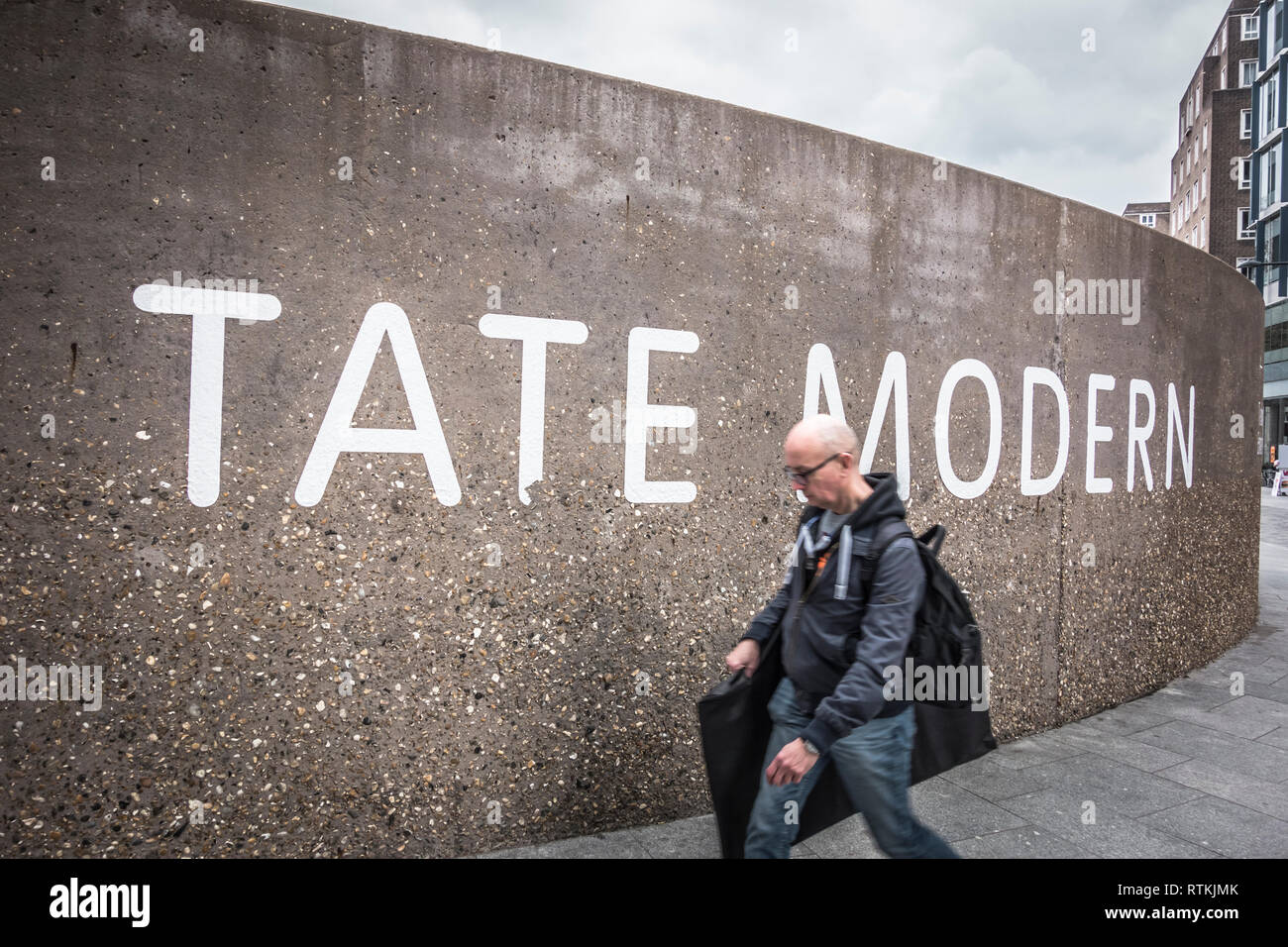 A man walking past signage on the Switch House, Tate Modern, London, UK ...