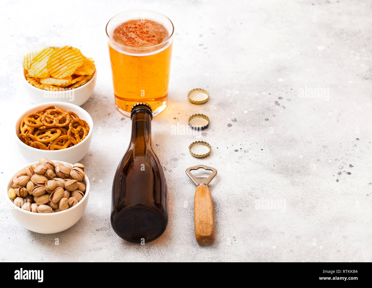Glass and bottle of craft lager beer with snack on stone kitchen ...