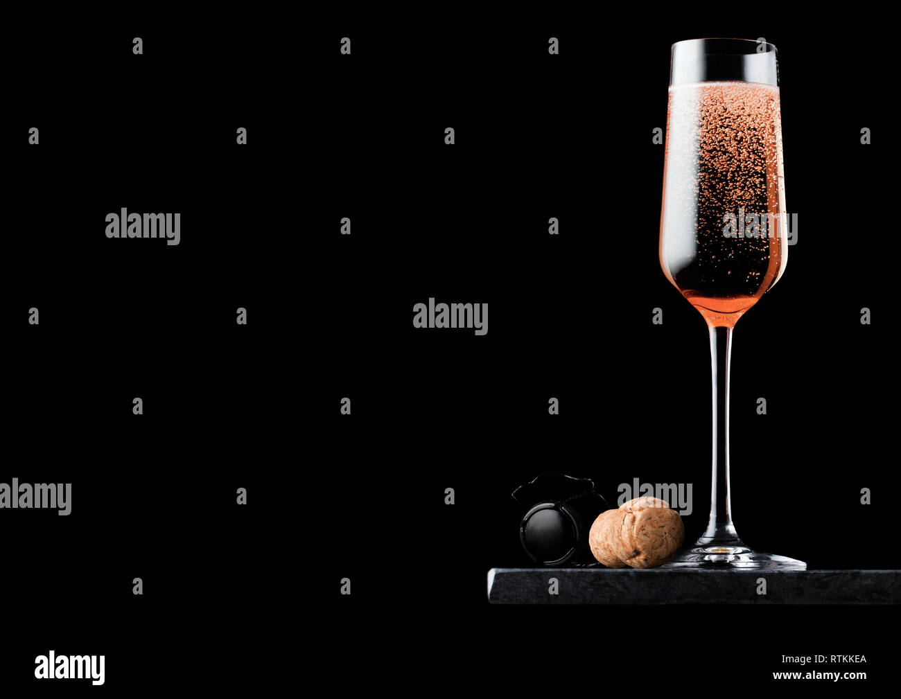 Elegant glass of pink rose champagne with cork and wire cage on black ...