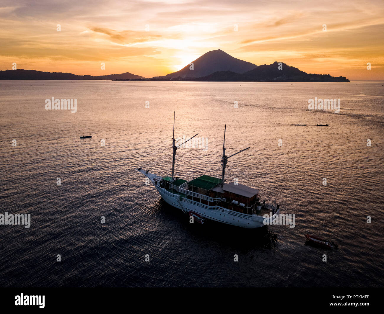 liveaboard dive boat, at sunset, Banda Api, an active volcanic island ...