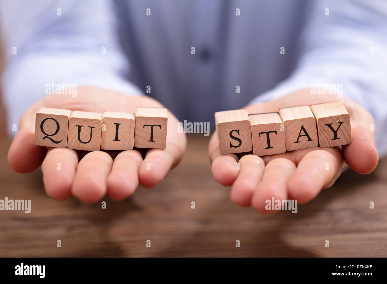 Close-up Businessman's Hand Holding Quit And Stay Blocks Over Wooden ...