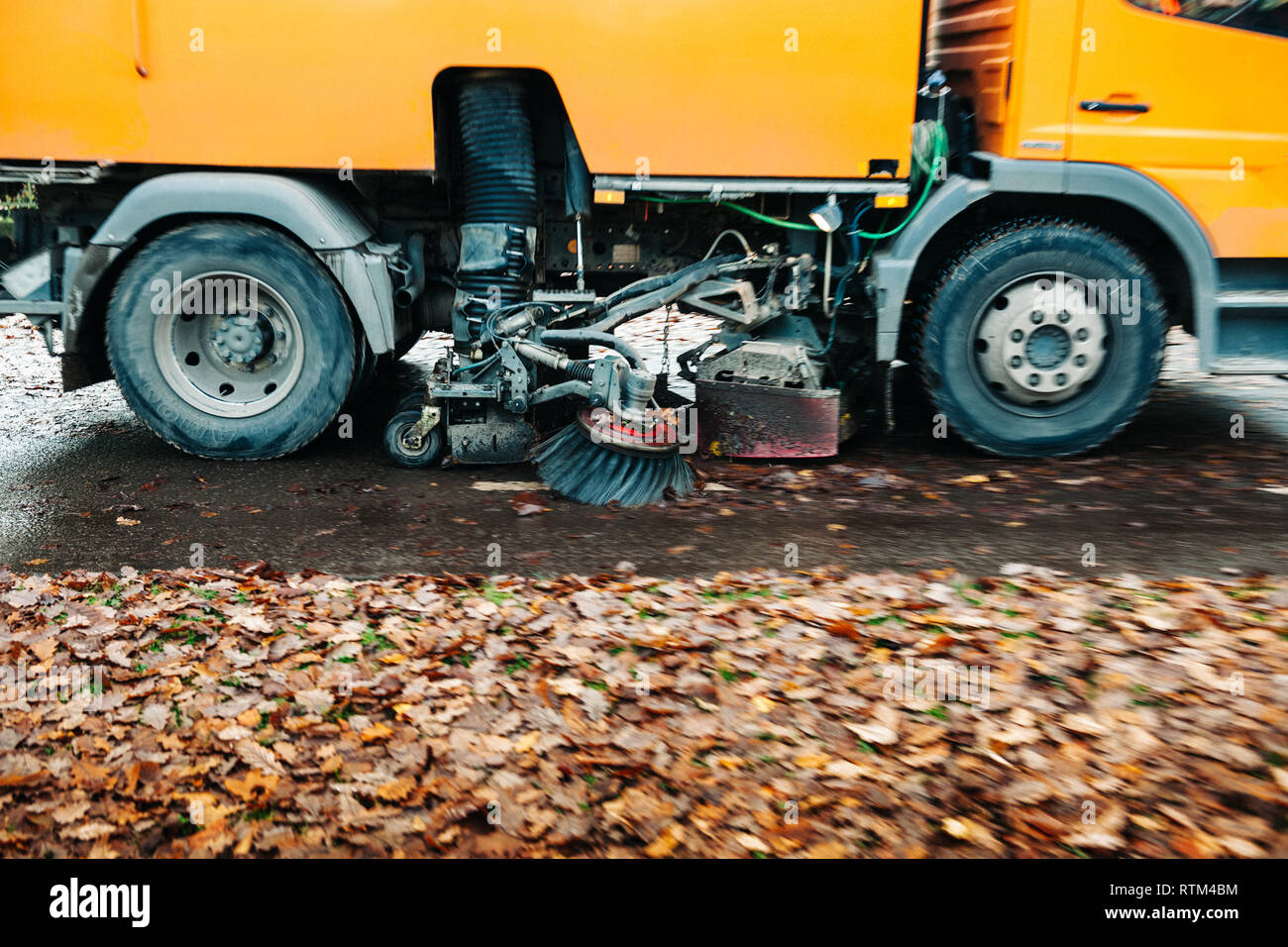 In motion orange street sweeper truck on the street working cleaning ...