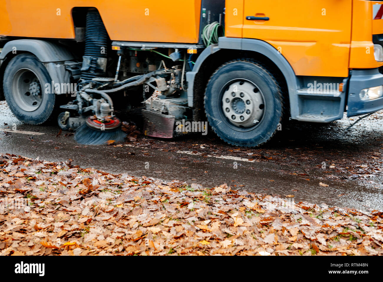 Modern street management with orange street sweeper truck on the street ...