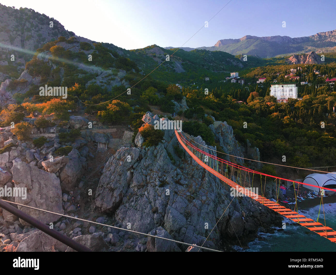View of suspension red rope bridge in mountain background Stock Photo ...