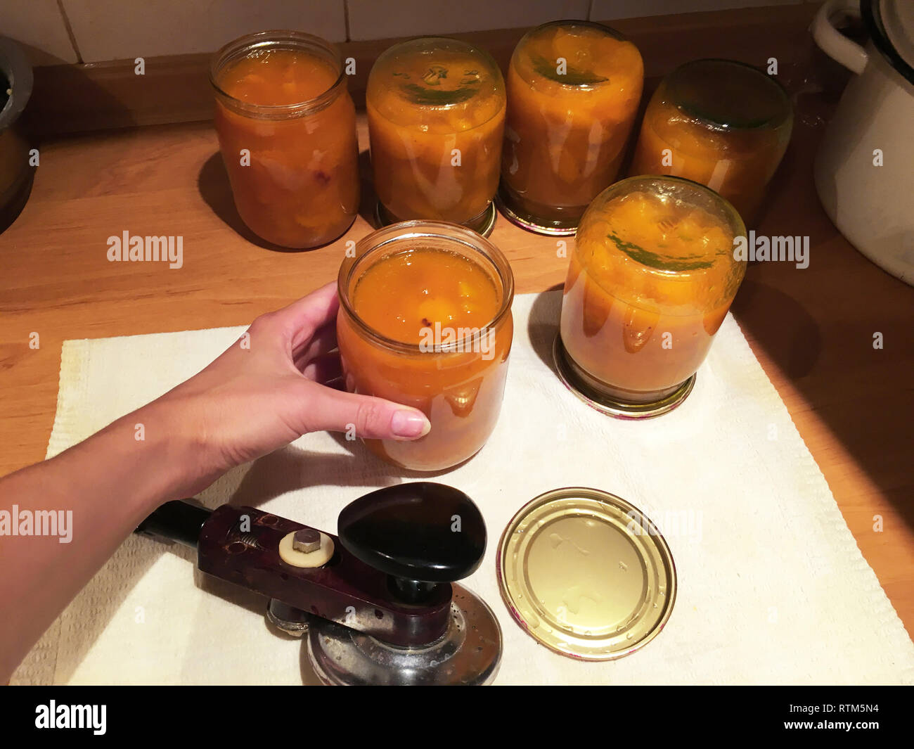 Home canning ham. Housewife filling peach, melon, pineapple and apricot ...