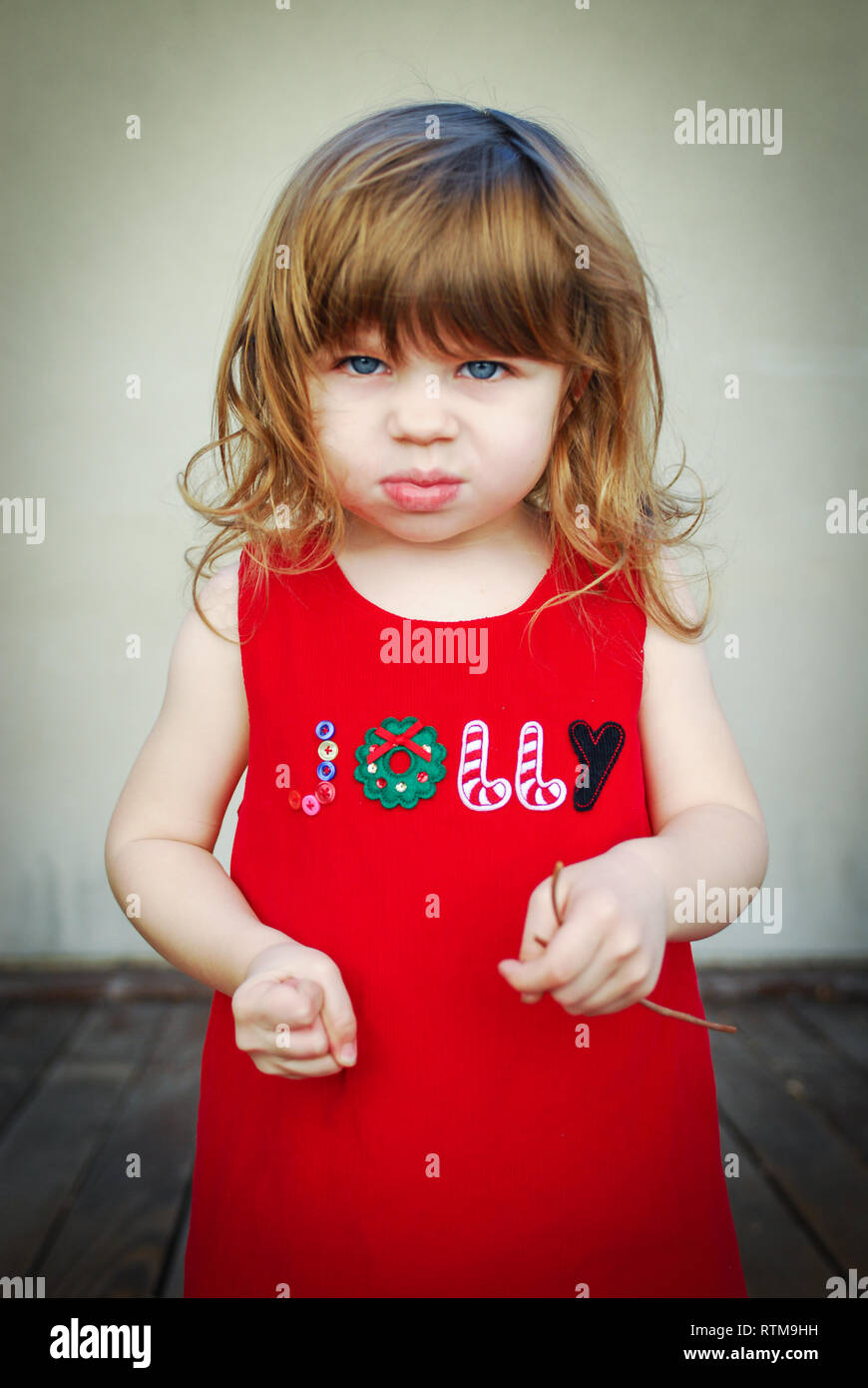 Angry looking toddler in Christmas dress Stock Photo - Alamy