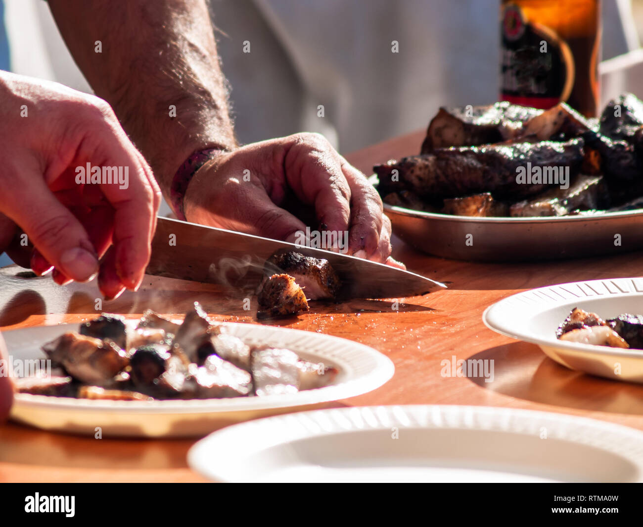 Unrecognizable person cutting meat with a knife and placing it on a ...