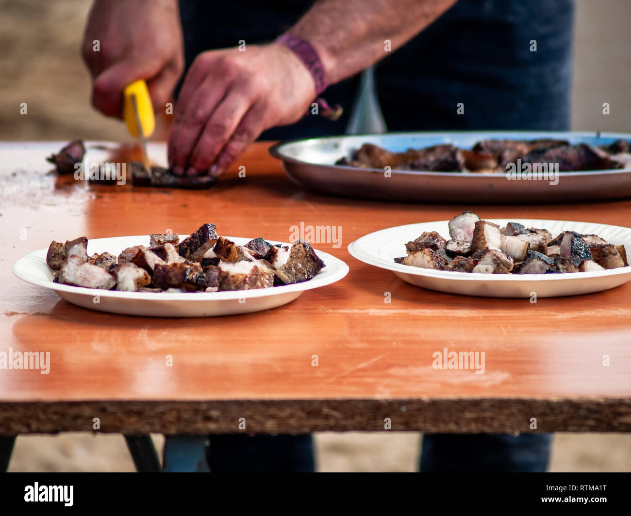 Unrecognizable person cutting meat with a knife and placing it on a ...
