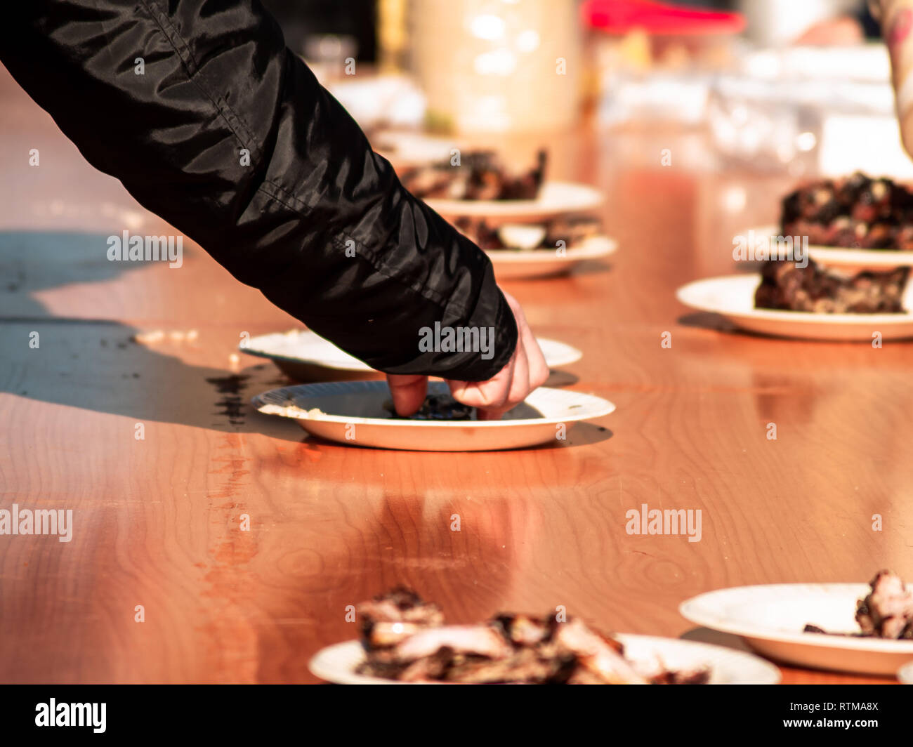 Unrecognizable person taking meat cooked from a paper plate in the ...