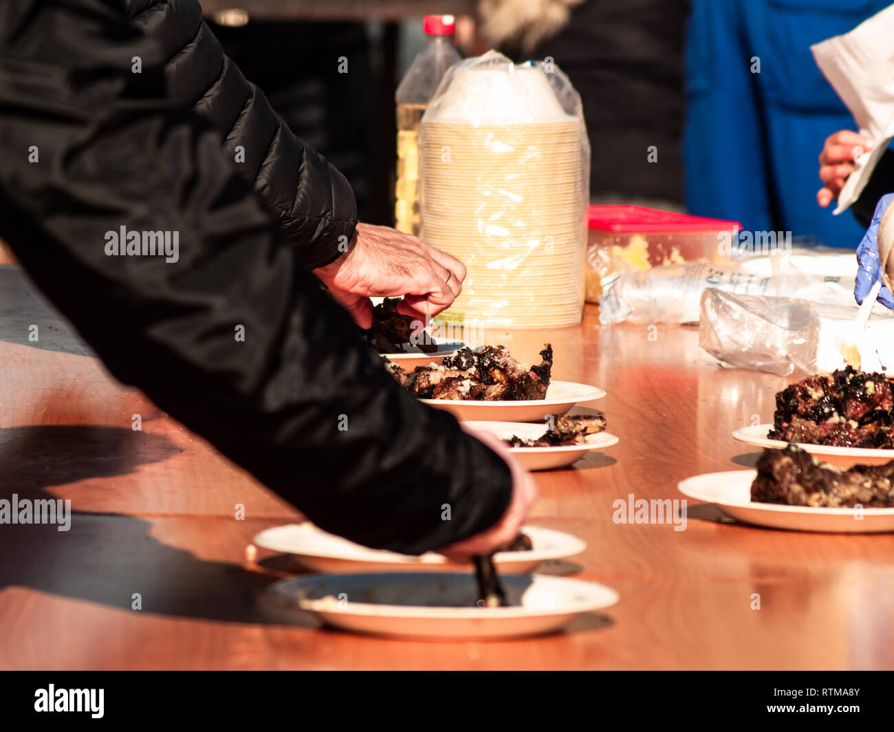 Unrecognizable person taking meat cooked from a paper plate in the ...