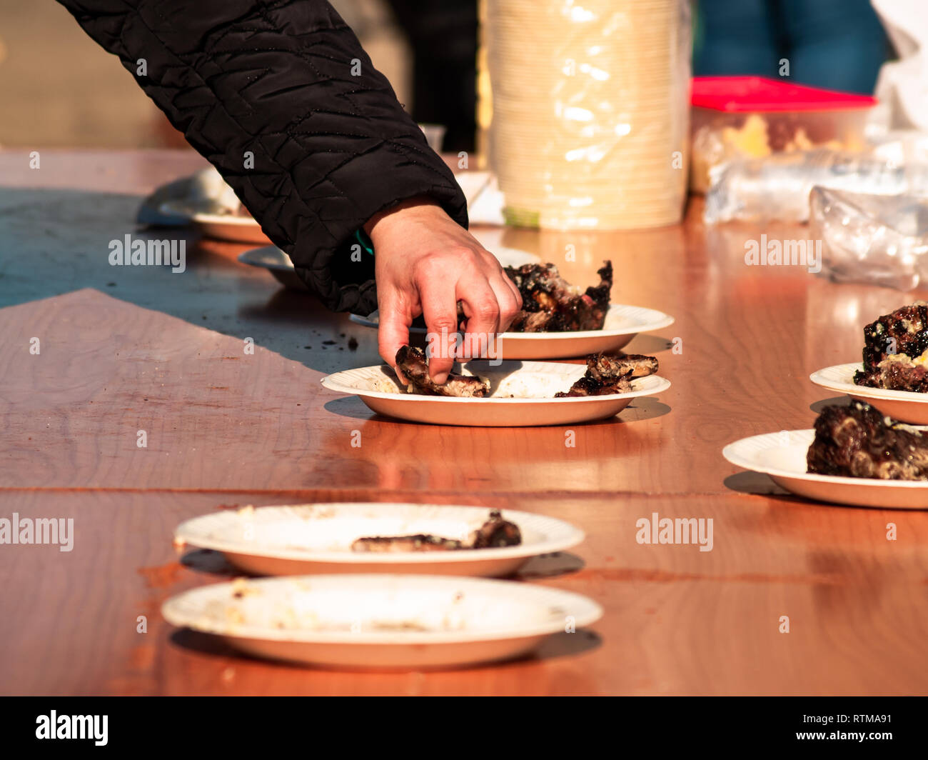 Unrecognizable person taking meat cooked from a paper plate in the ...