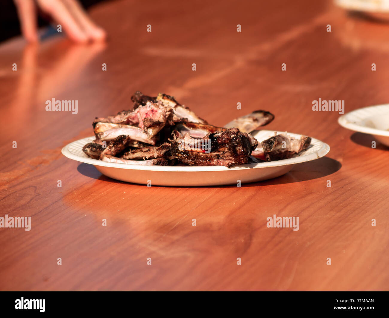 Unrecognizable person taking meat cooked from a paper plate in the ...