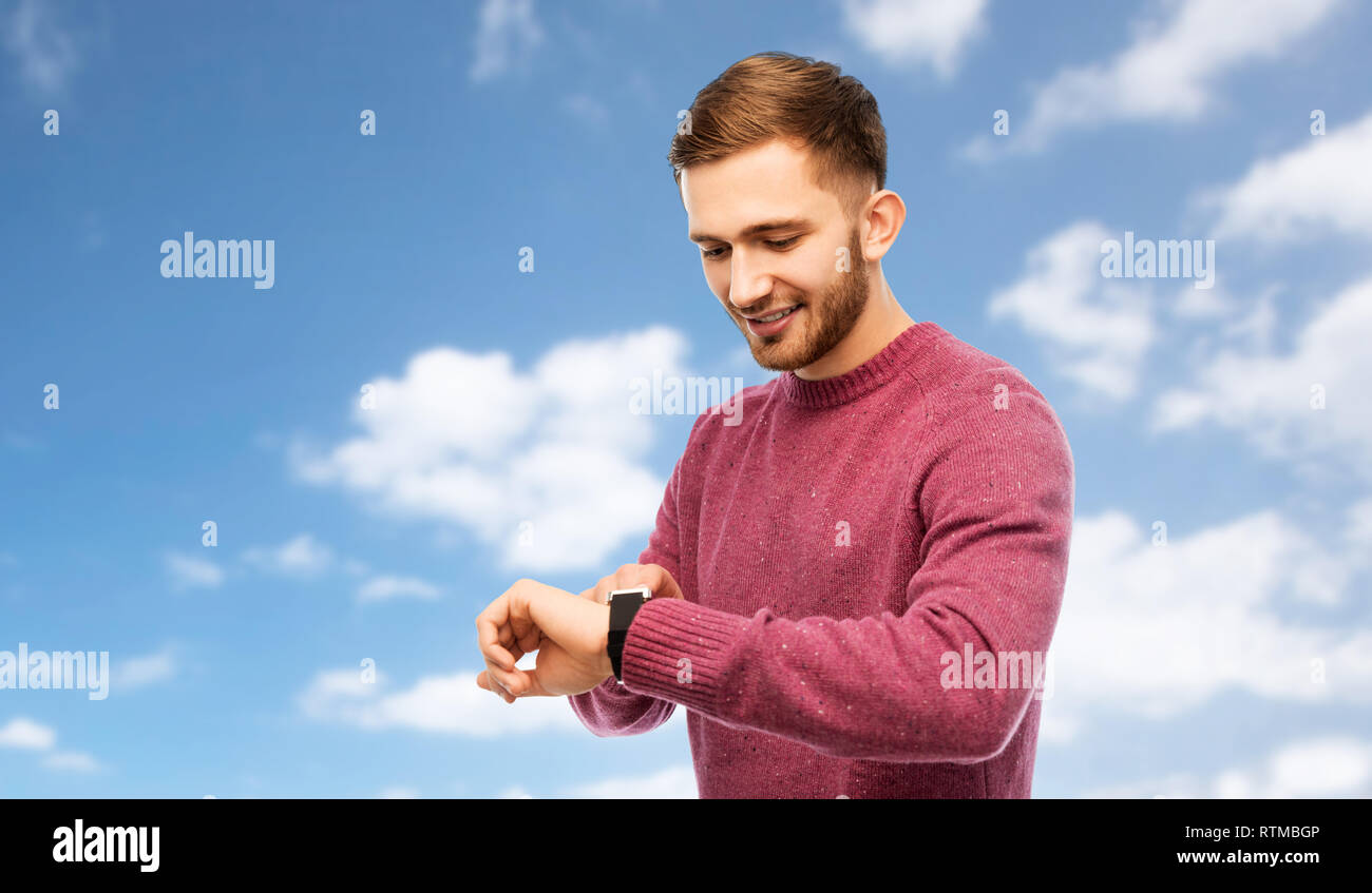 smiling young man checking time on wristwatch Stock Photo - Alamy