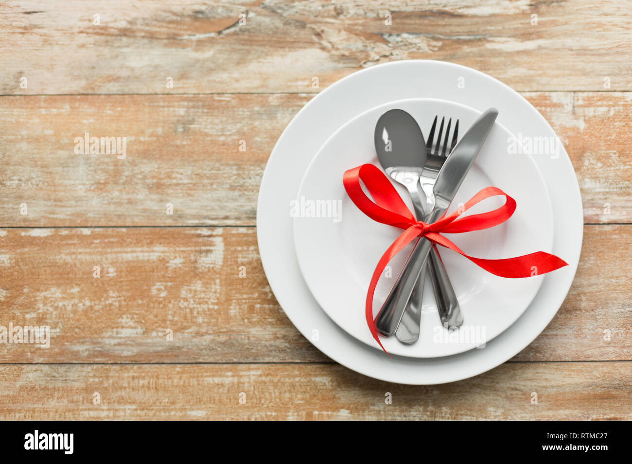 cutlery tied with red ribbon on set of plates Stock Photo - Alamy