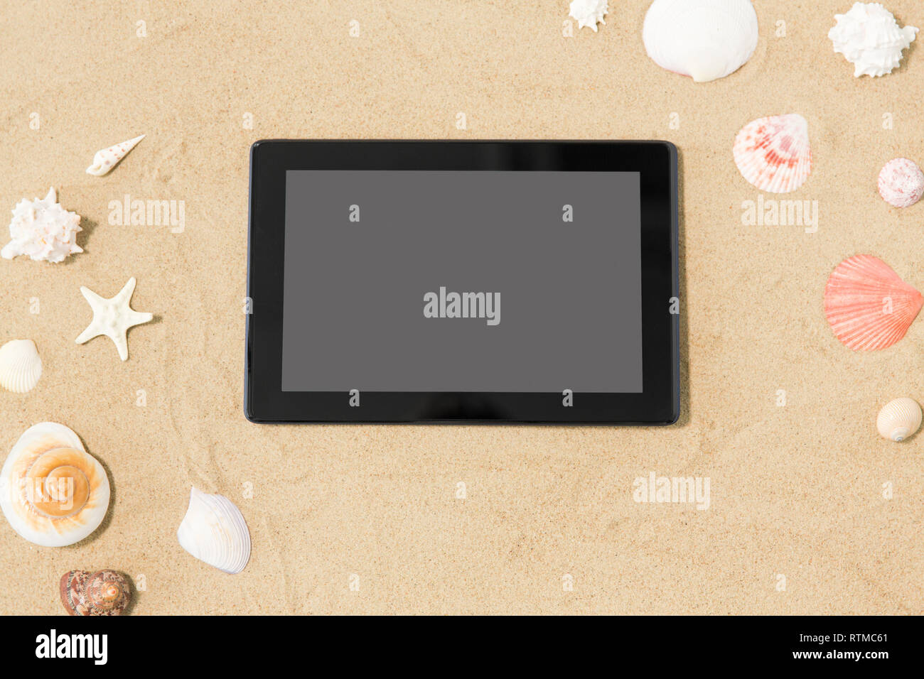 tablet computer and seashells on beach sand Stock Photo - Alamy