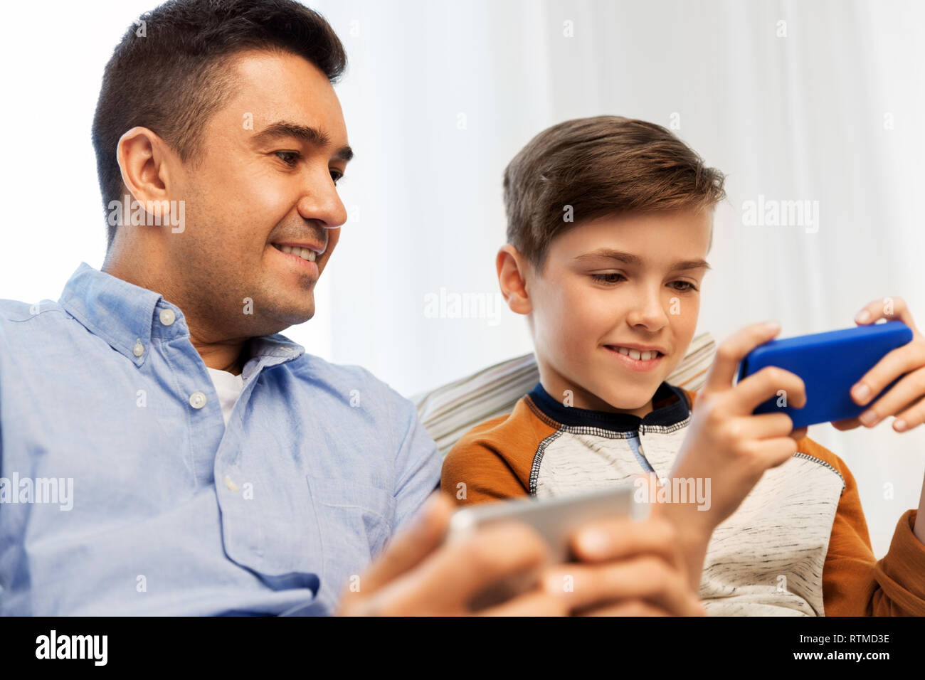 happy father and son with smartphones at home Stock Photo - Alamy