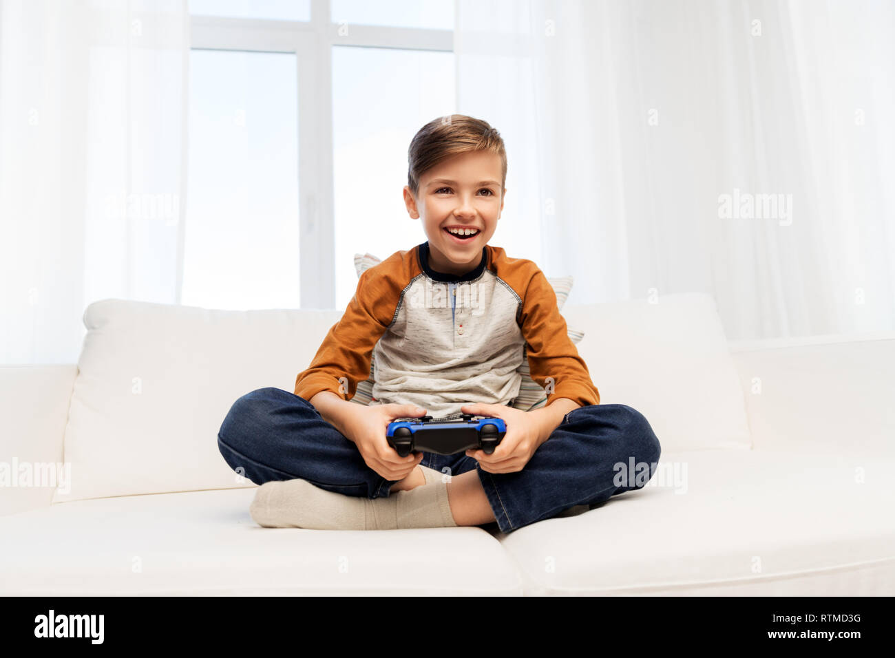 happy boy with gamepad playing video game at home Stock Photo - Alamy