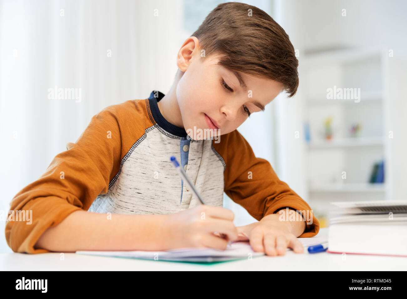 boy doing homework and writing to notebook at home Stock Photo - Alamy