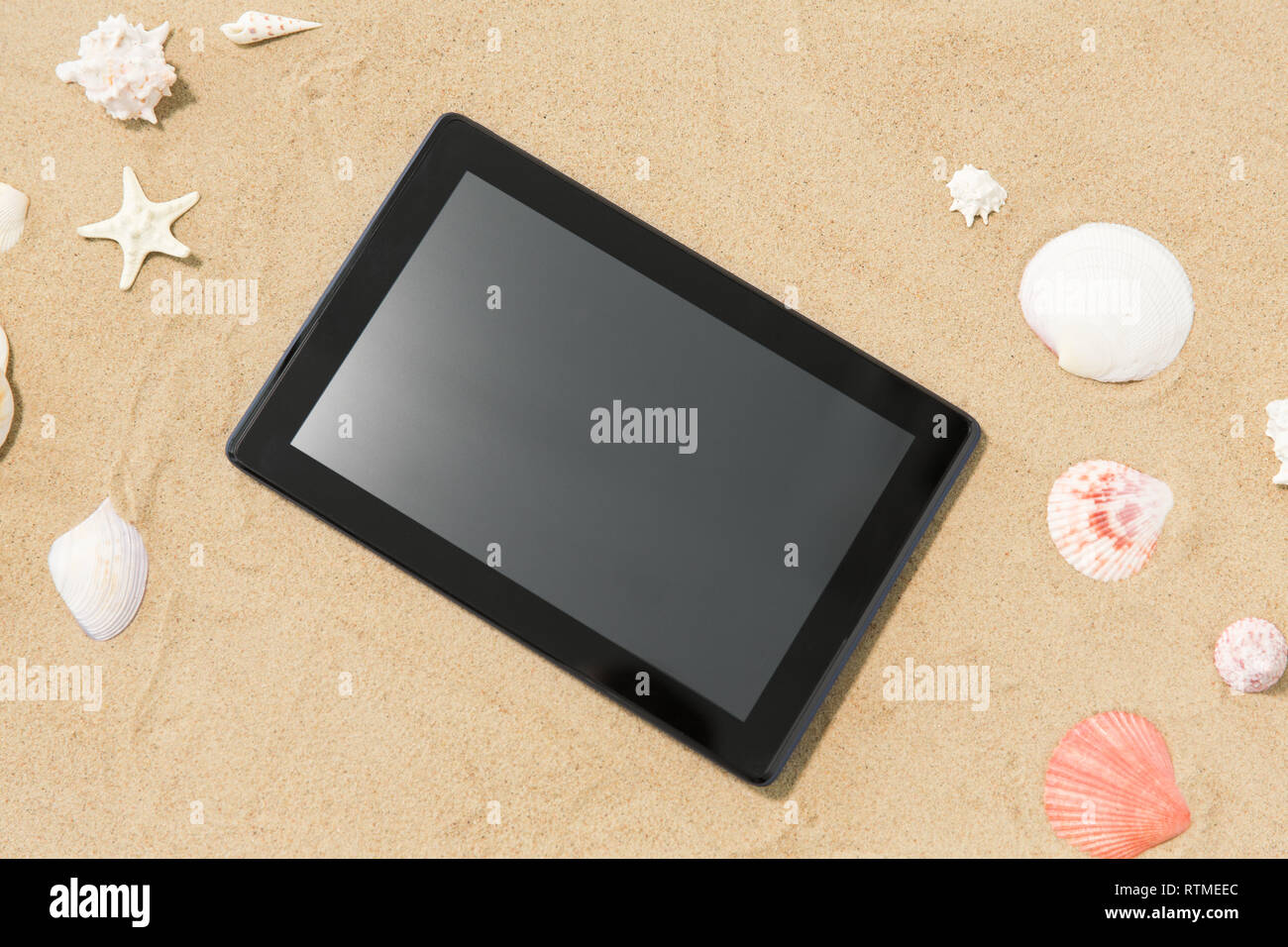 tablet computer and seashells on beach sand Stock Photo - Alamy