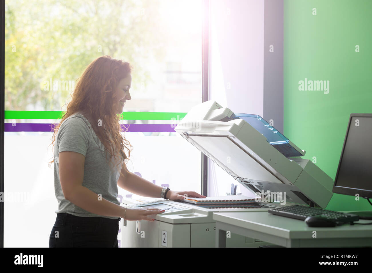 A young student at a copy center taking some copies for her final exams ...