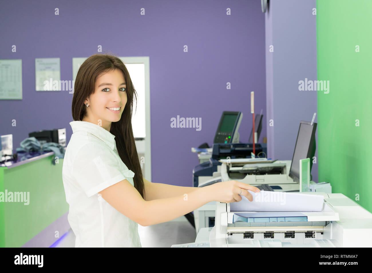 A young student at a copy center taking some copies for her final exams ...