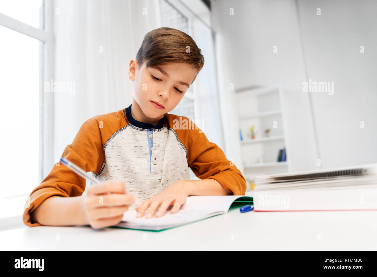 boy doing homework and writing to notebook at home Stock Photo - Alamy