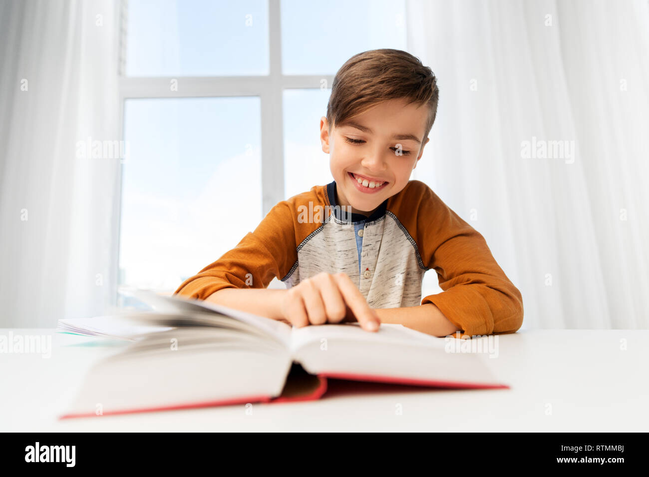 student boy reading book at home table Stock Photo - Alamy