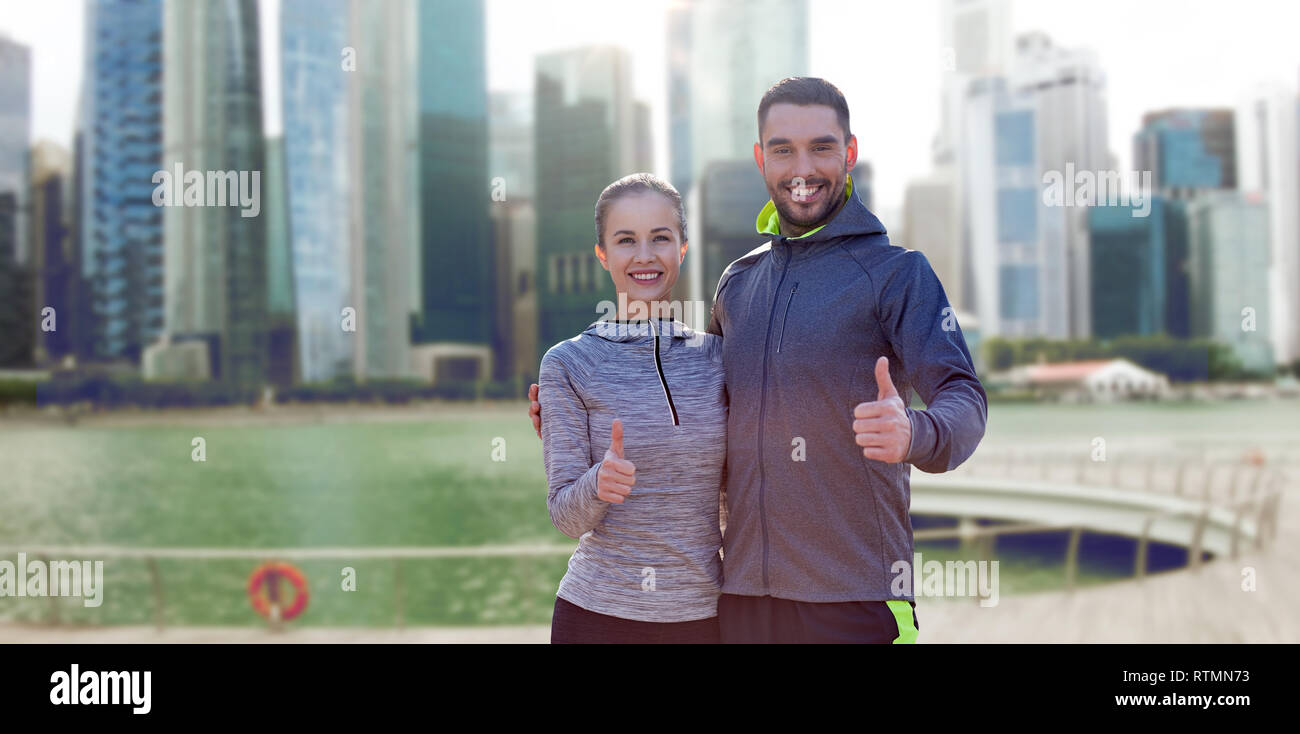 happy couple showing thumbs up over singapore city Stock Photo - Alamy