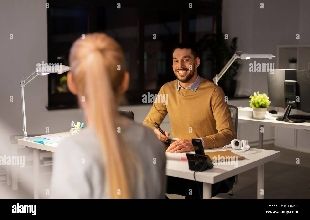 designer with laptop talking to coworker at office Stock Photo - Alamy