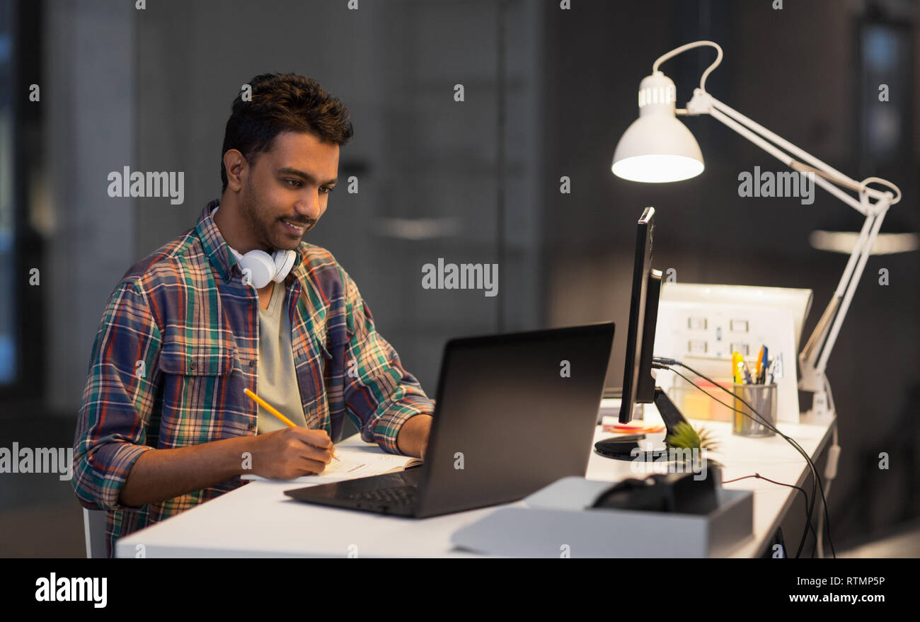 creative man with laptop working at night office Stock Photo - Alamy