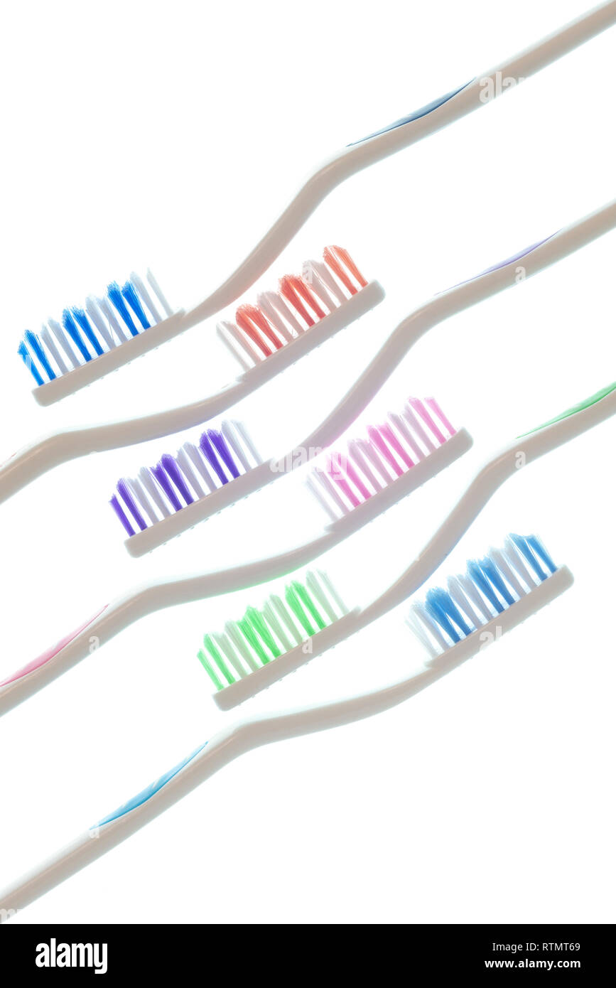 Vertical side view shot of six colorful toothbrushes with white handles ...