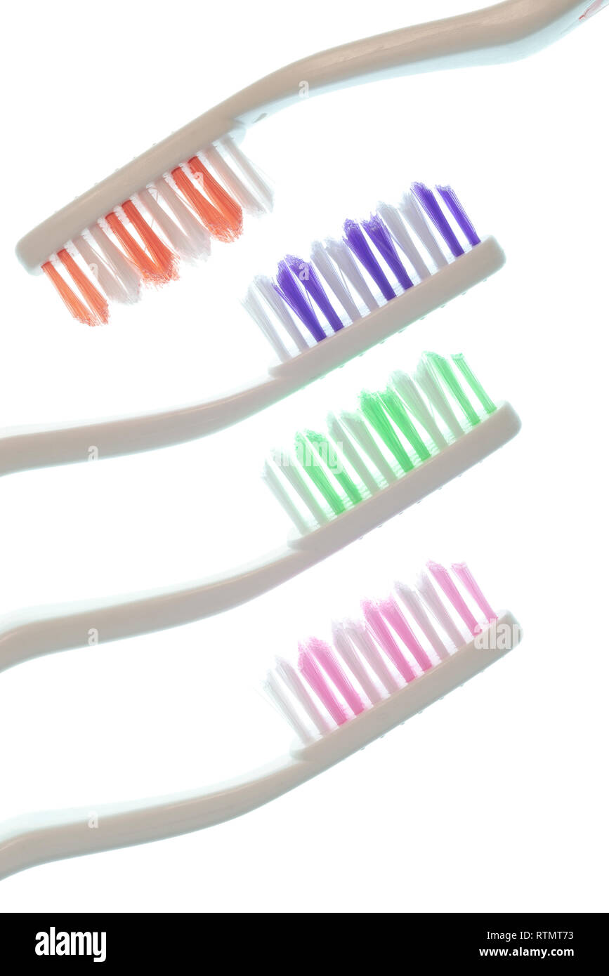 Vertical side view shot of four colorful toothbrushes with white ...
