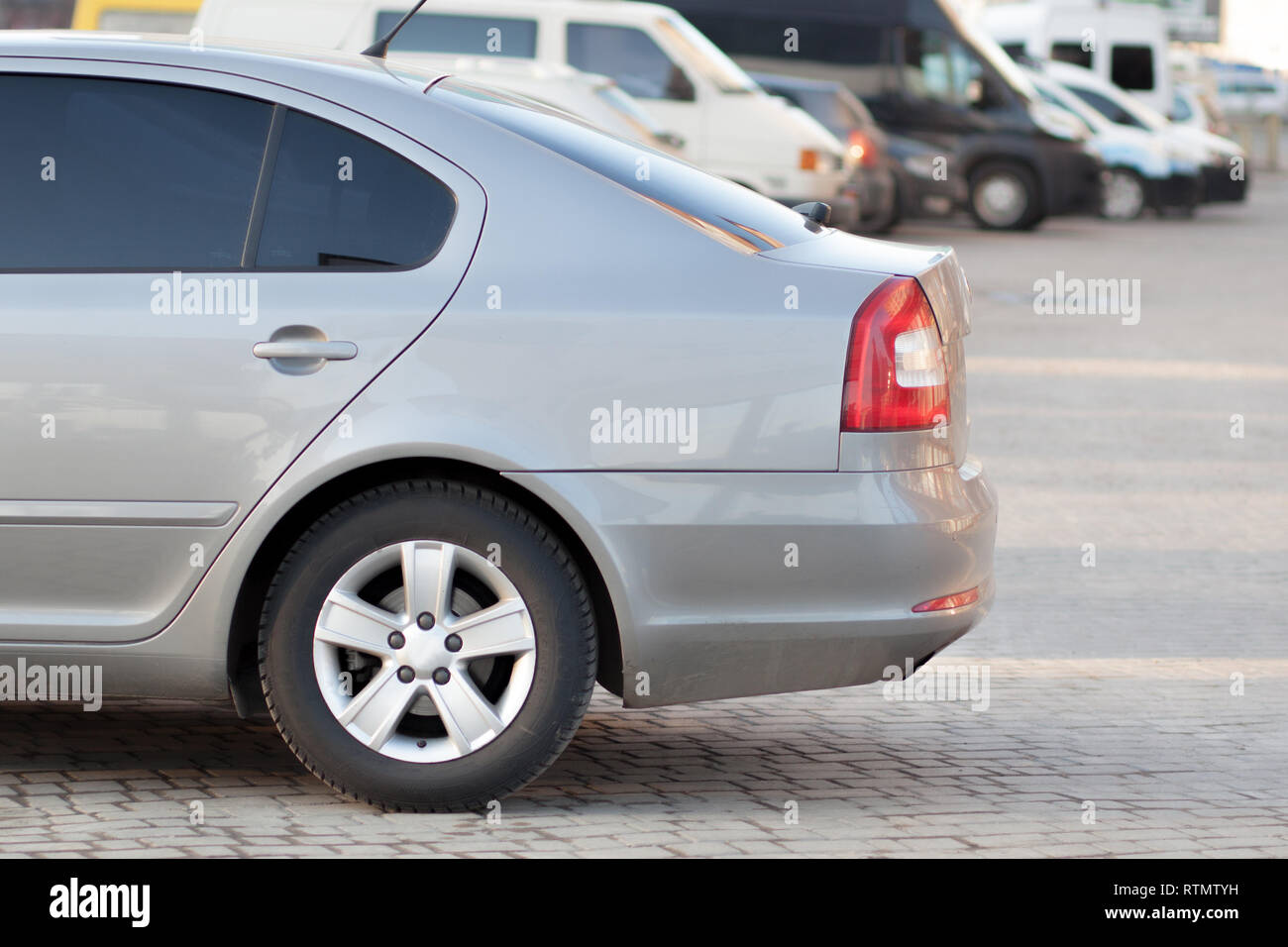 Side view of silver car parked in paved parking lot area on blurred ...