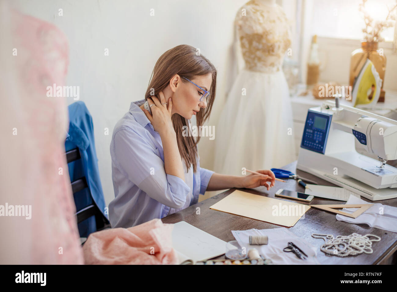 Skilled beautiful dressmaker in fashion atelier in stylish eyeglasses ...