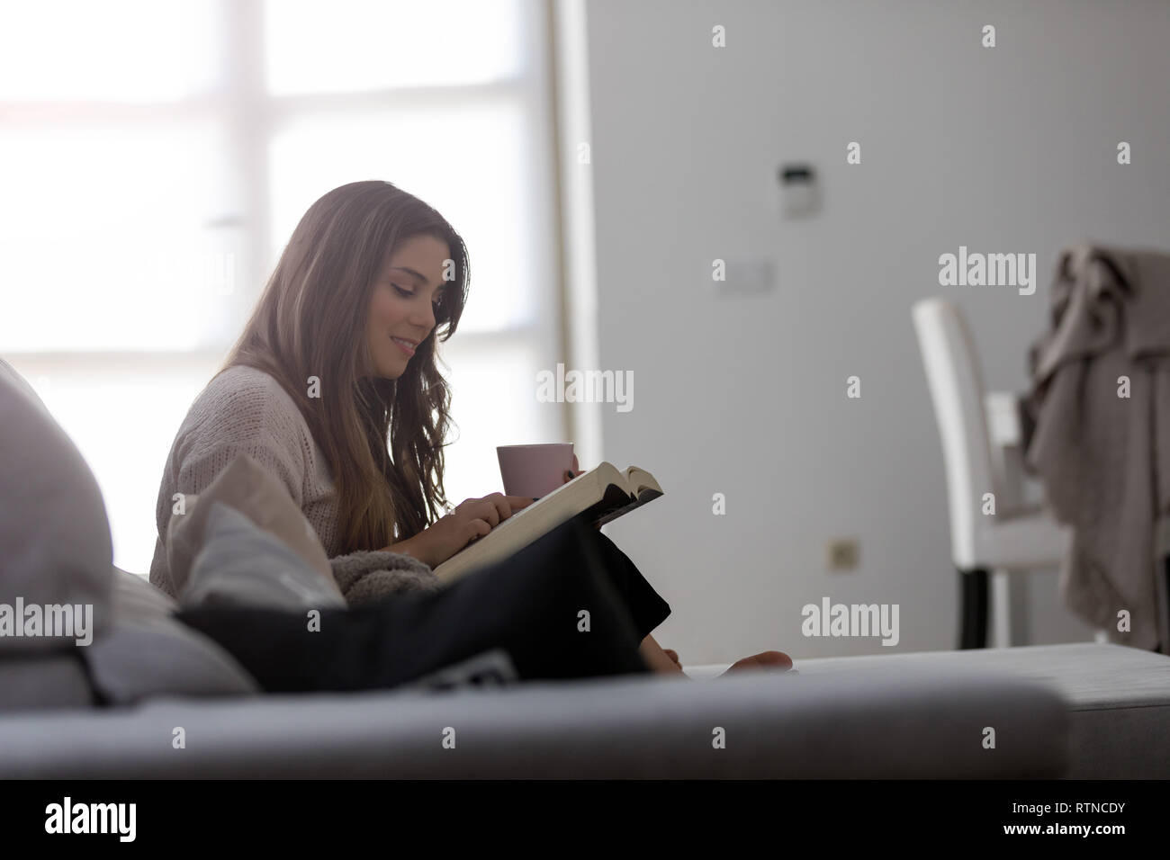 Beautiful young woman relaxing at home reading a book Stock Photo - Alamy