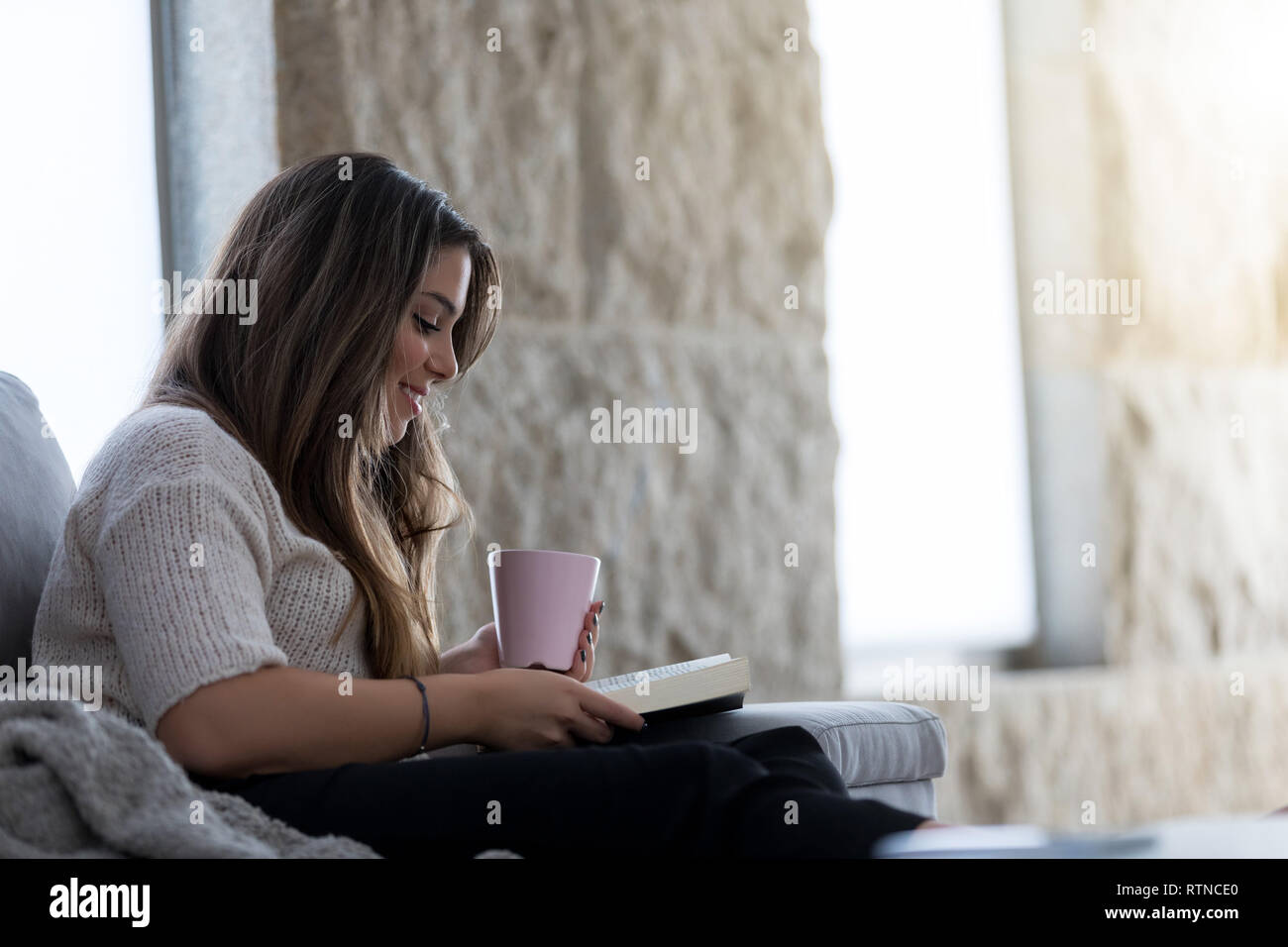 Beautiful young woman relaxing at home reading a book Stock Photo - Alamy