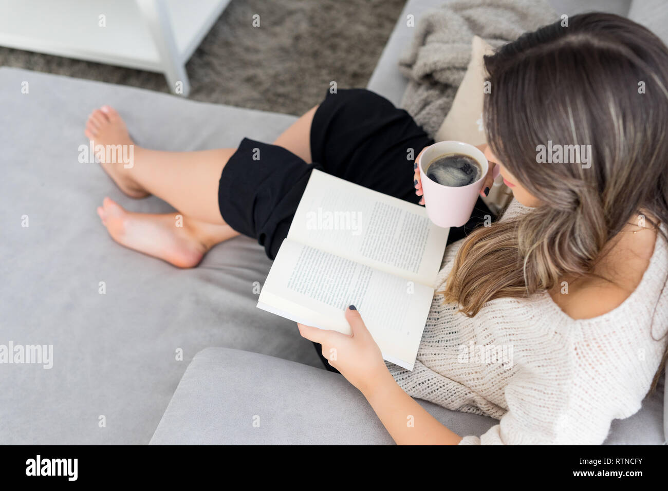 Beautiful young woman relaxing at home reading a book Stock Photo - Alamy