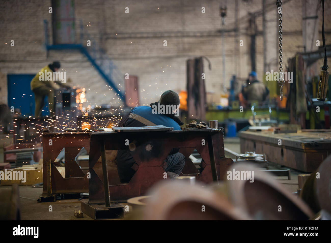 Industrial concept. A man sitting at his workplace and using grinder ...