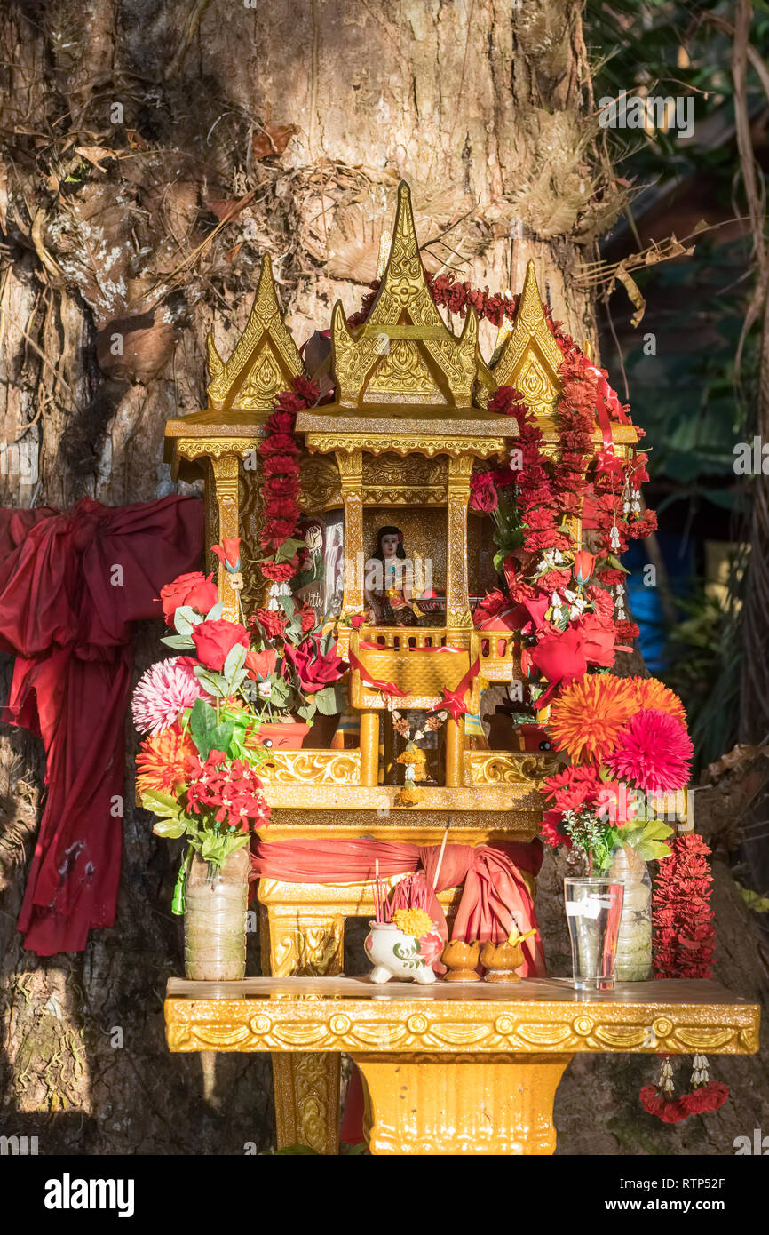 Spirit house in Thailand with flower garlands near the big tree Stock ...